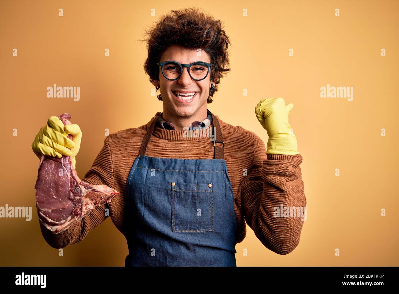 Young handsome butcher man holding meet steak standing over isolated ...