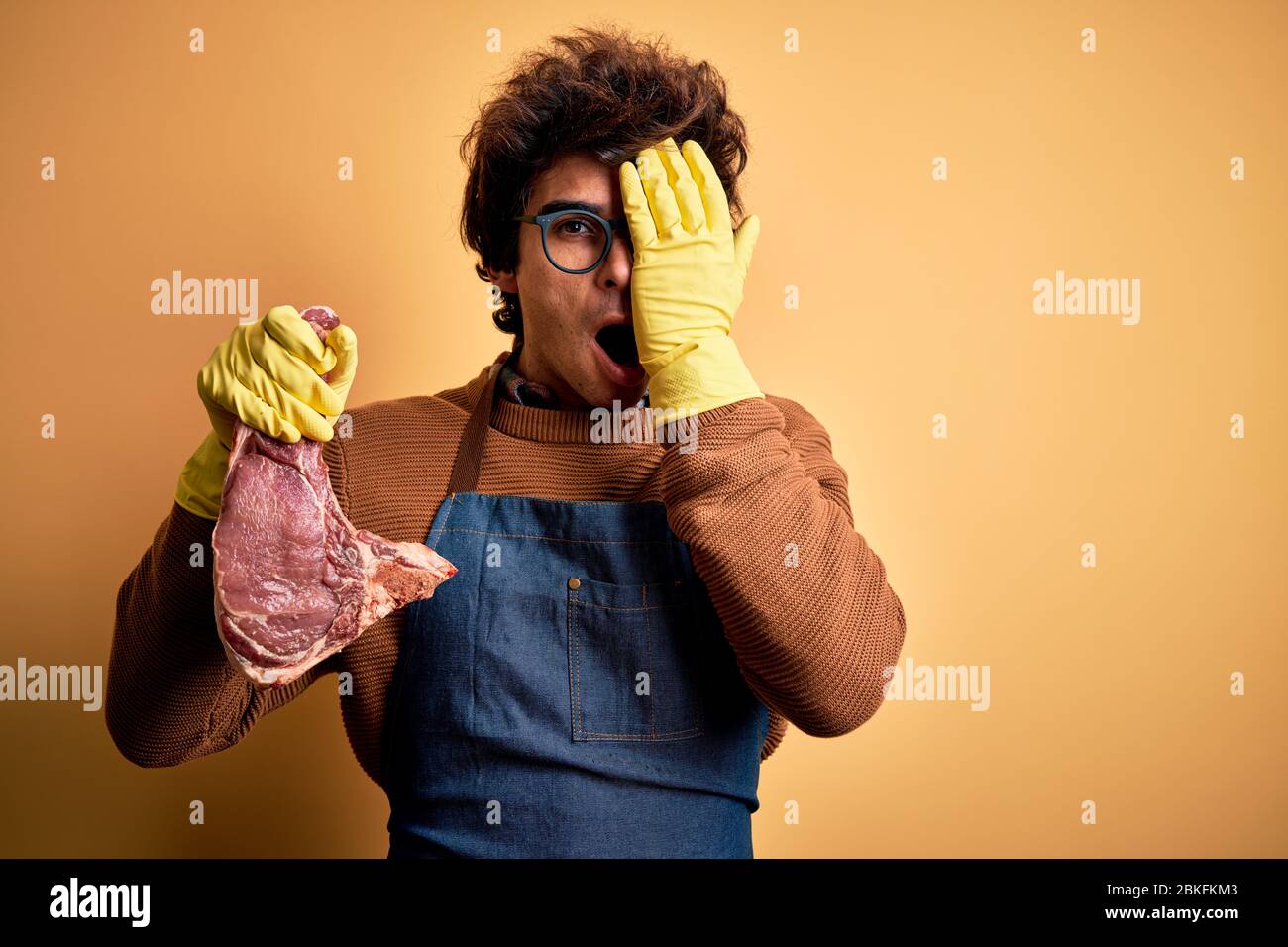 Young handsome butcher man holding meet steak standing over isolated ...