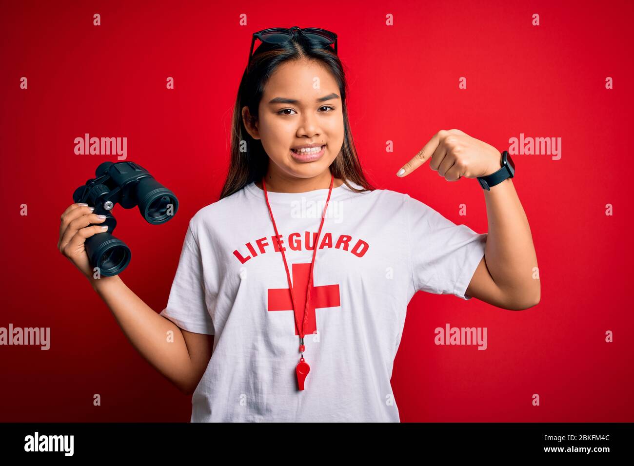 Young asian lifeguard girl wearing t-shirt with red cross using whistle ...