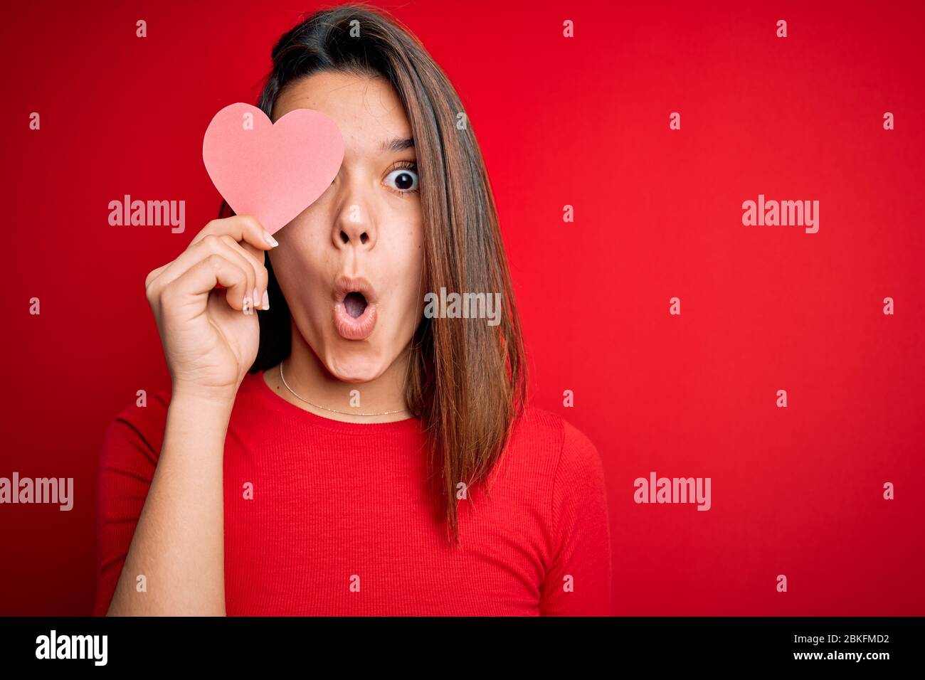Young beautiful brunette romantic girl holding red paper heart shape ...