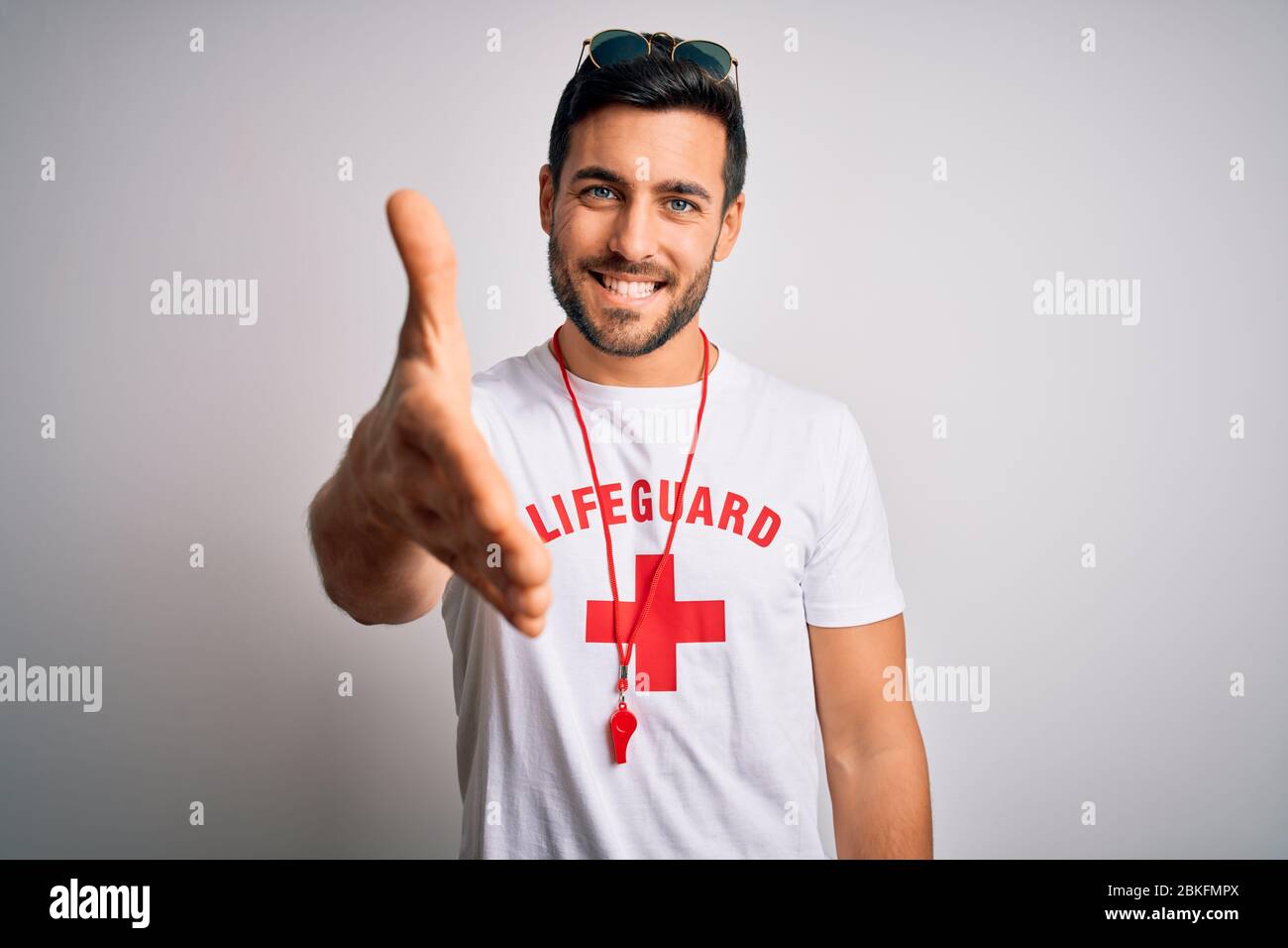 Young handsome lifeguard man with beard wearing t-shirt with red cross ...