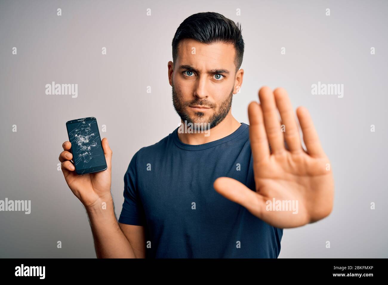 Young handsome man holding broken and cracked smartphone screen over ...