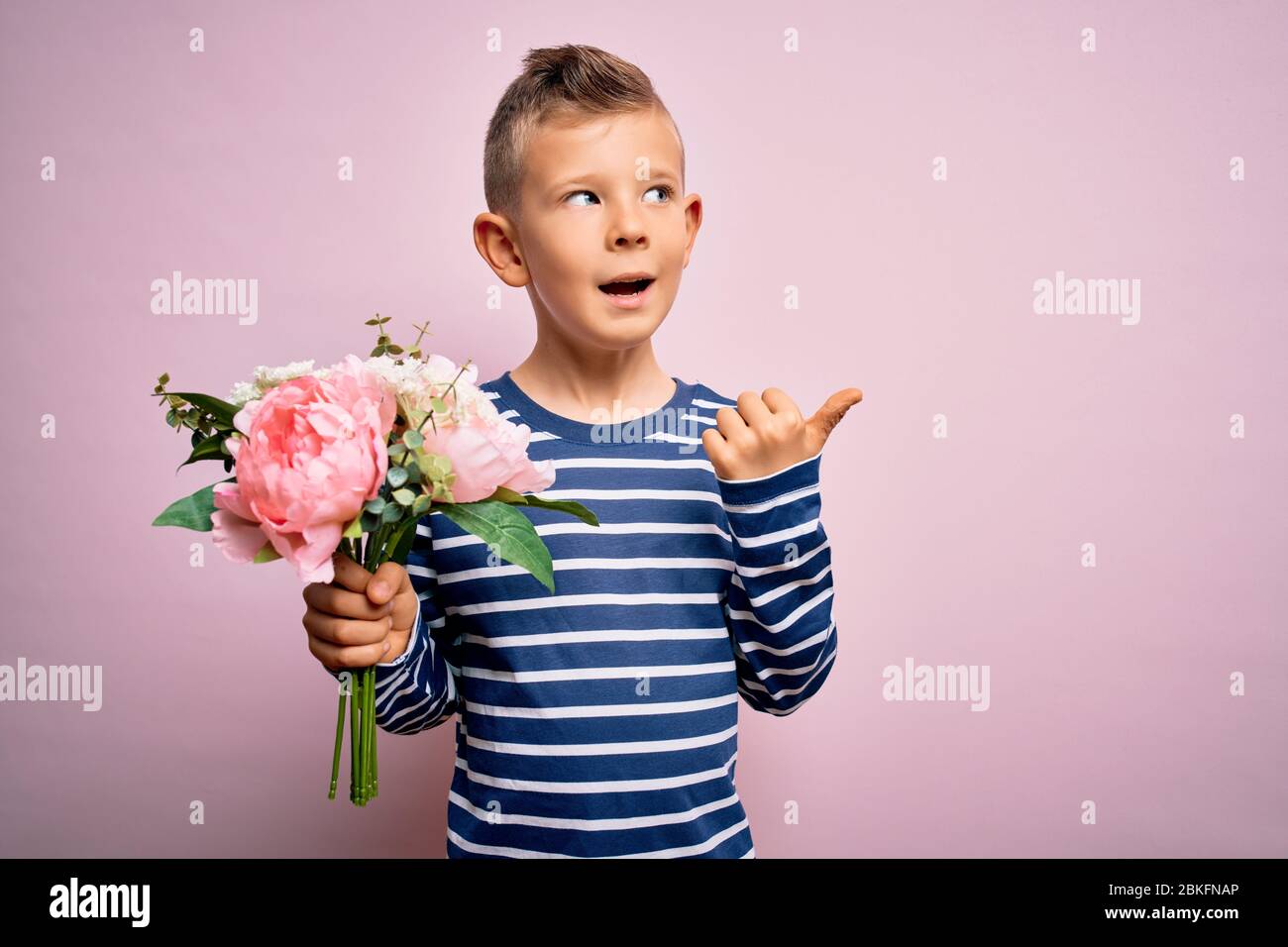 Young little caucasian kid holding romantic and cute bouquet of flowers ...