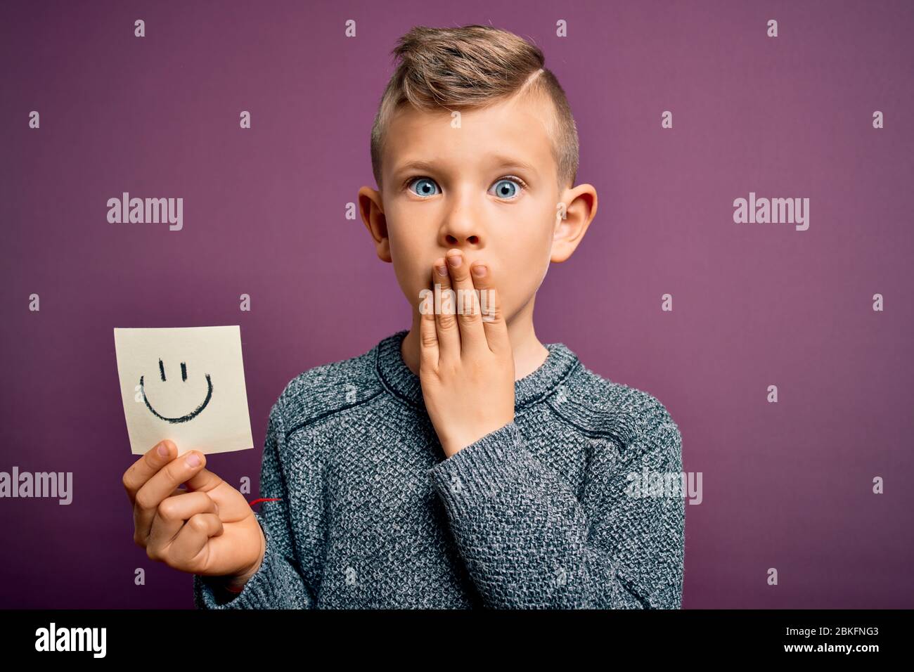 Young little caucasian kid showing smiley face on a paper note as happy ...