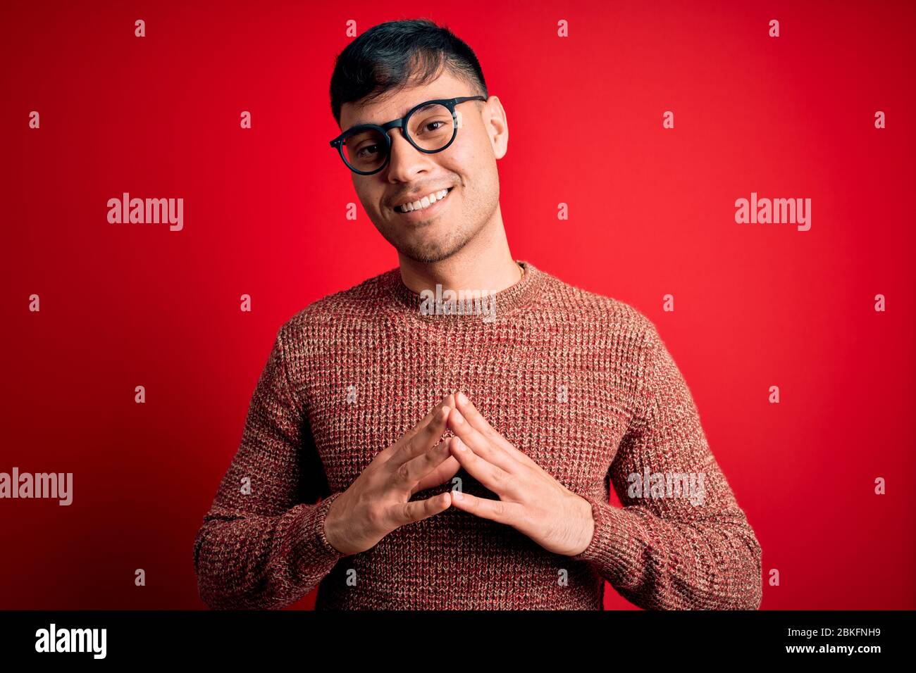 Young handsome hispanic man wearing nerd glasses over red background ...