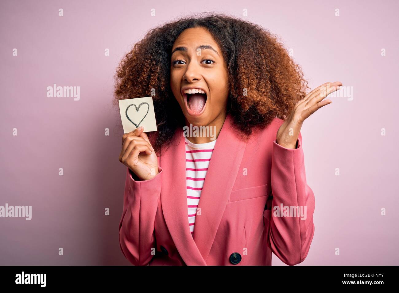 Young african american woman with afro hair holding paper with heart ...