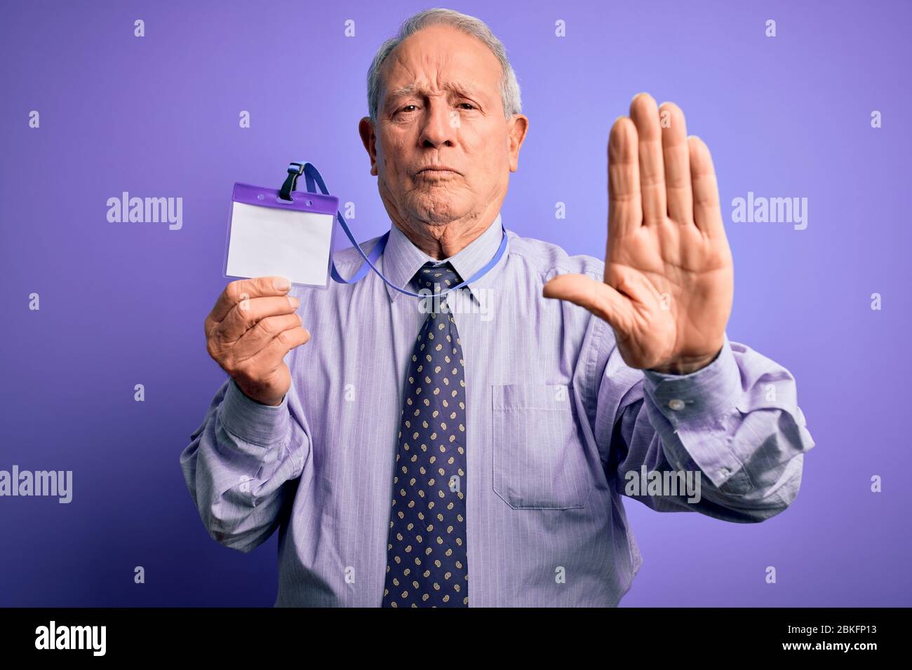 Senior grey haired business man holding identification tag over purple ...