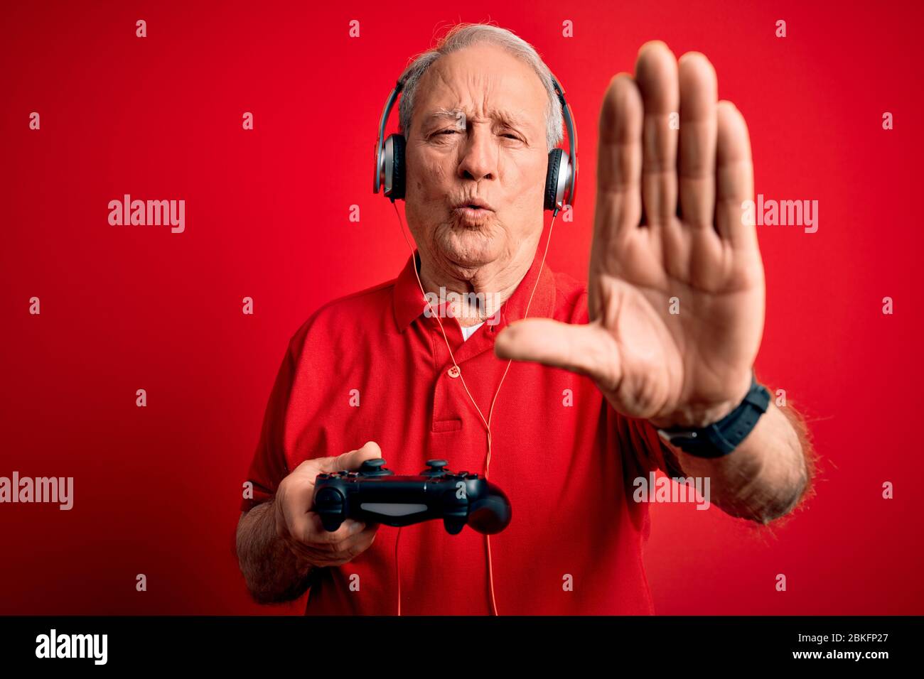 Senior grey haired gamer man playing video games using gamepad joystick ...