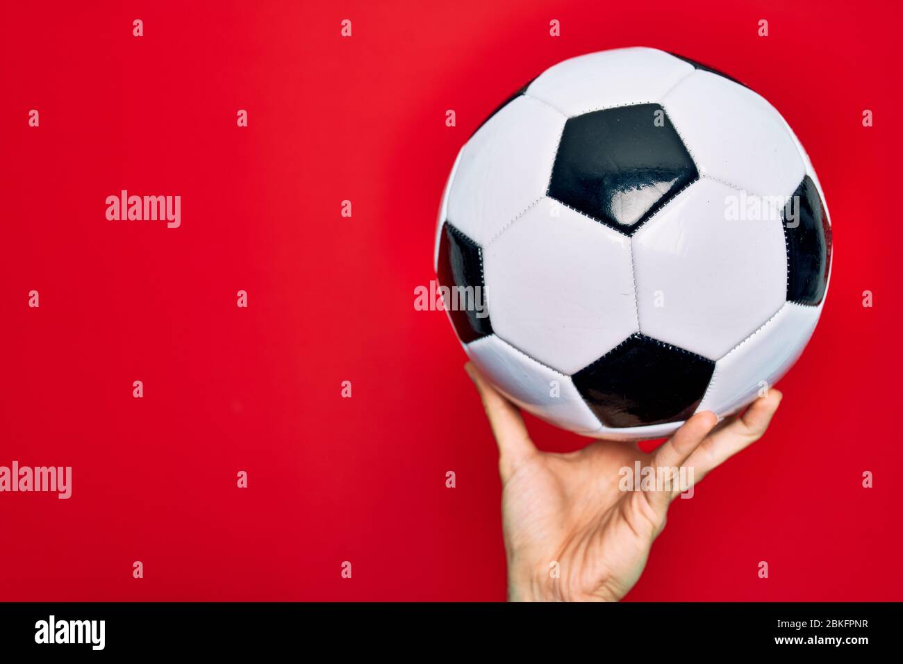 Beautiful hand of man holding football ball over isolated red ...