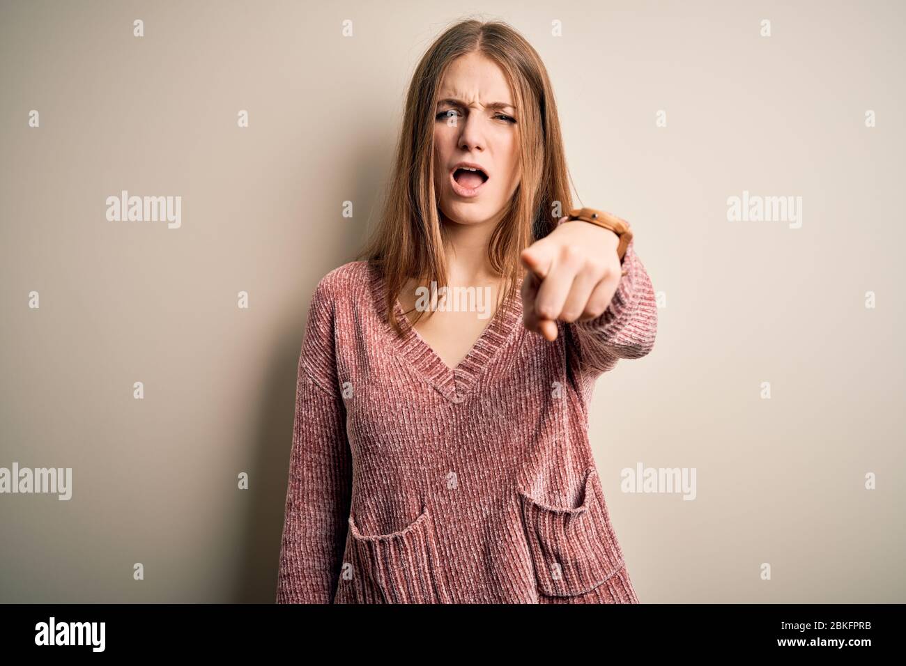 Young beautiful redhead woman wearing pink casual sweater over isolated ...