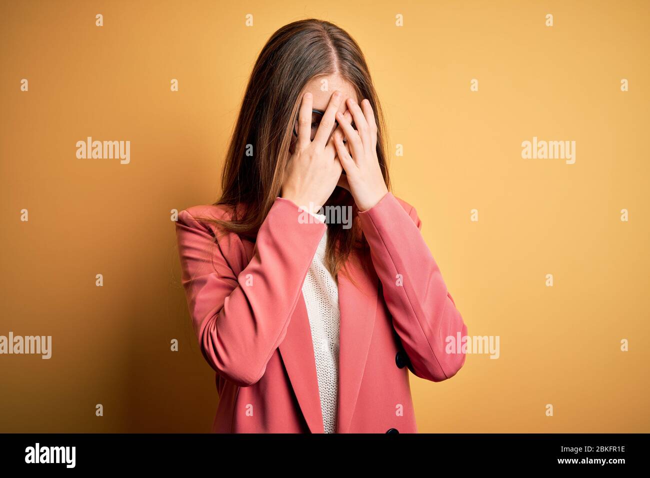 Young beautiful redhead woman wearing jacket and glasses over isolated ...