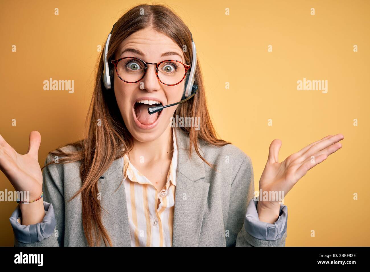 Young redhead call center agent woman overworked wearing glasses using ...