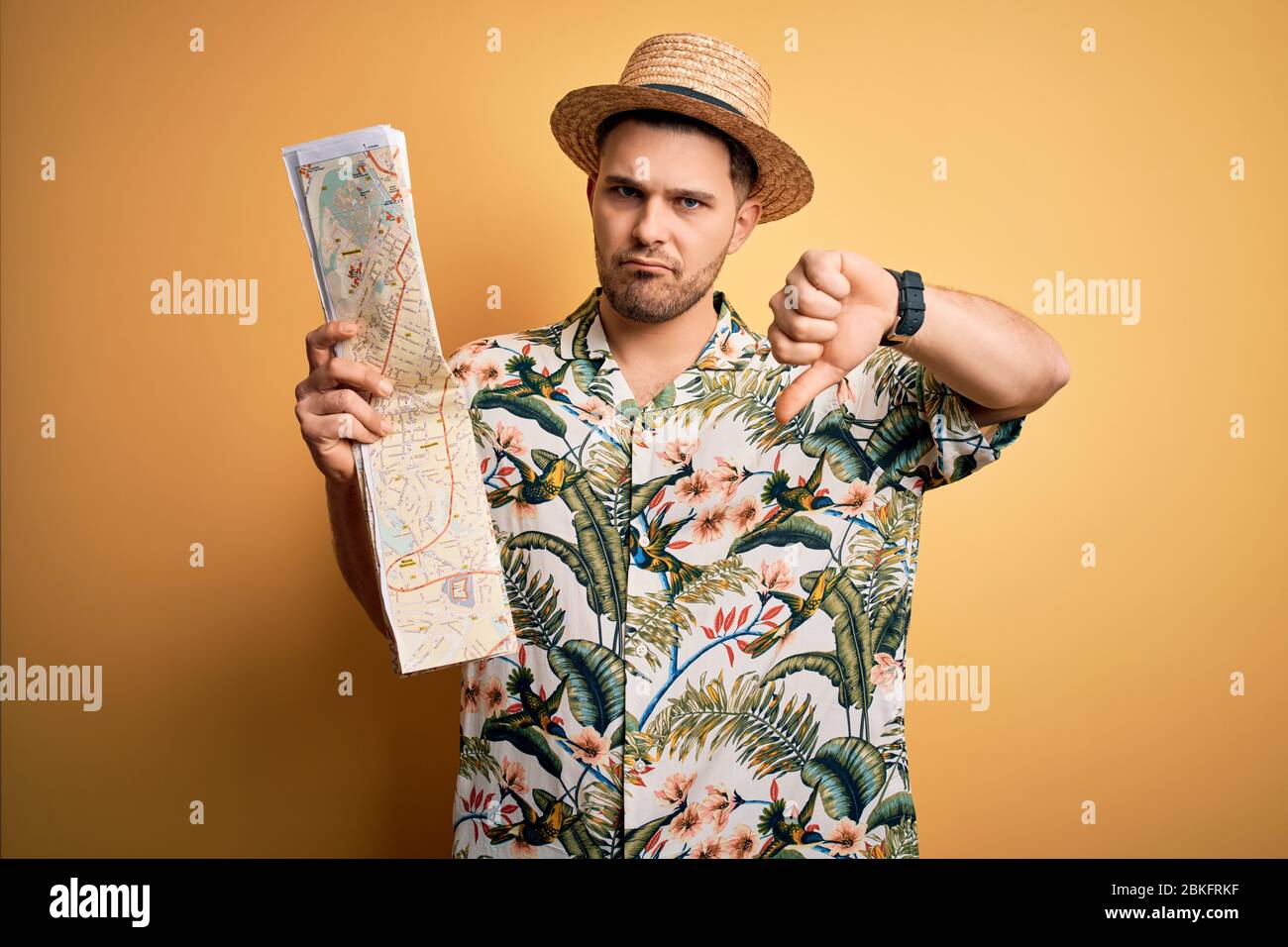 Young man on vacation wearing summer hat holding and looking at tourist ...