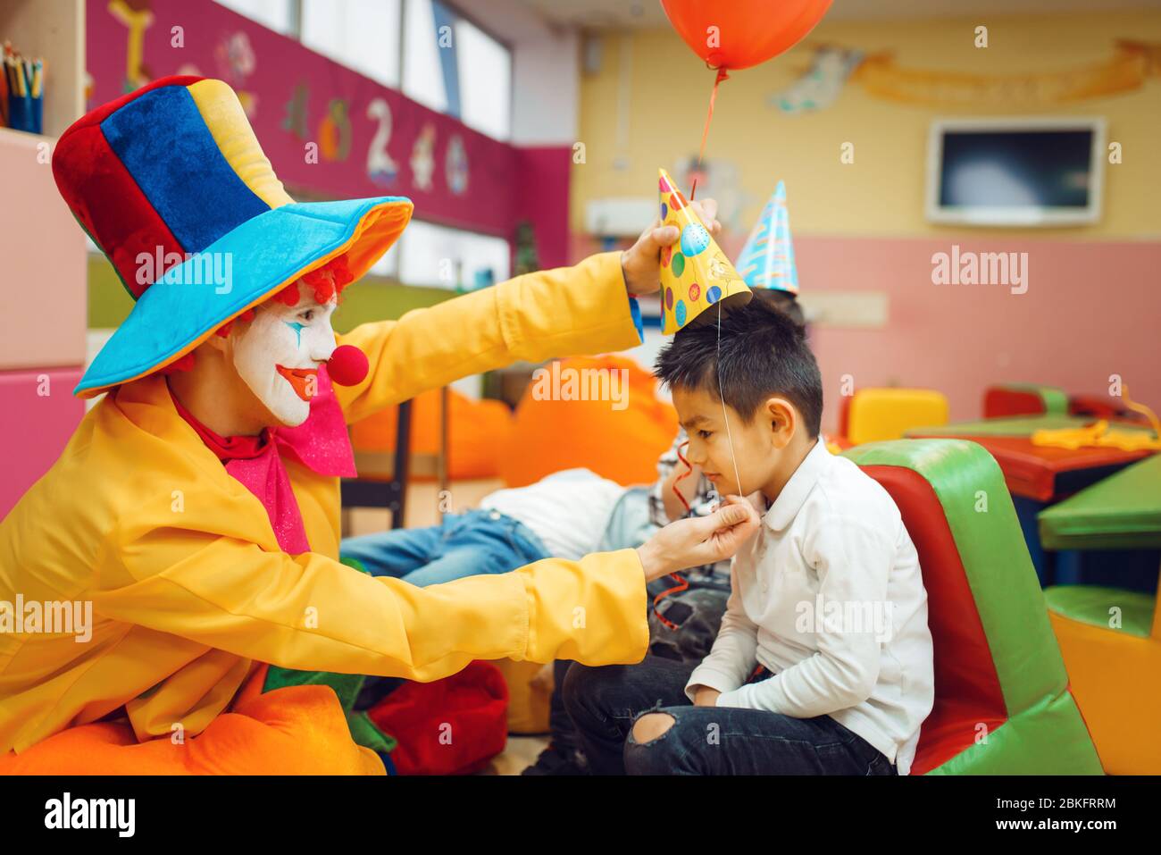 Funny clown puts a cap on the little boy's head Stock Photo - Alamy