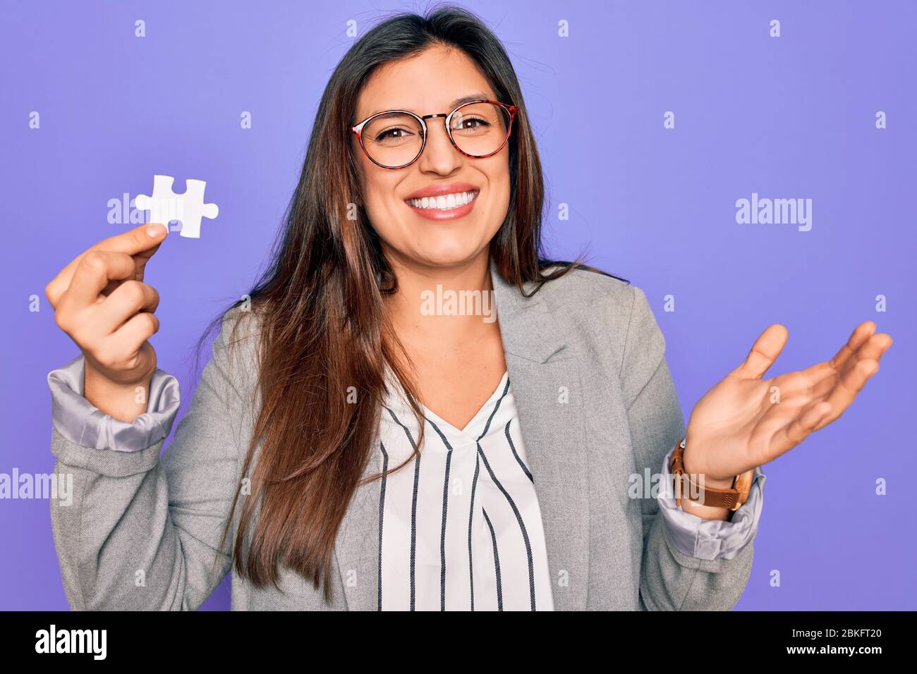 Young hispanic business woman holding puzzle peace as cooperation and ...
