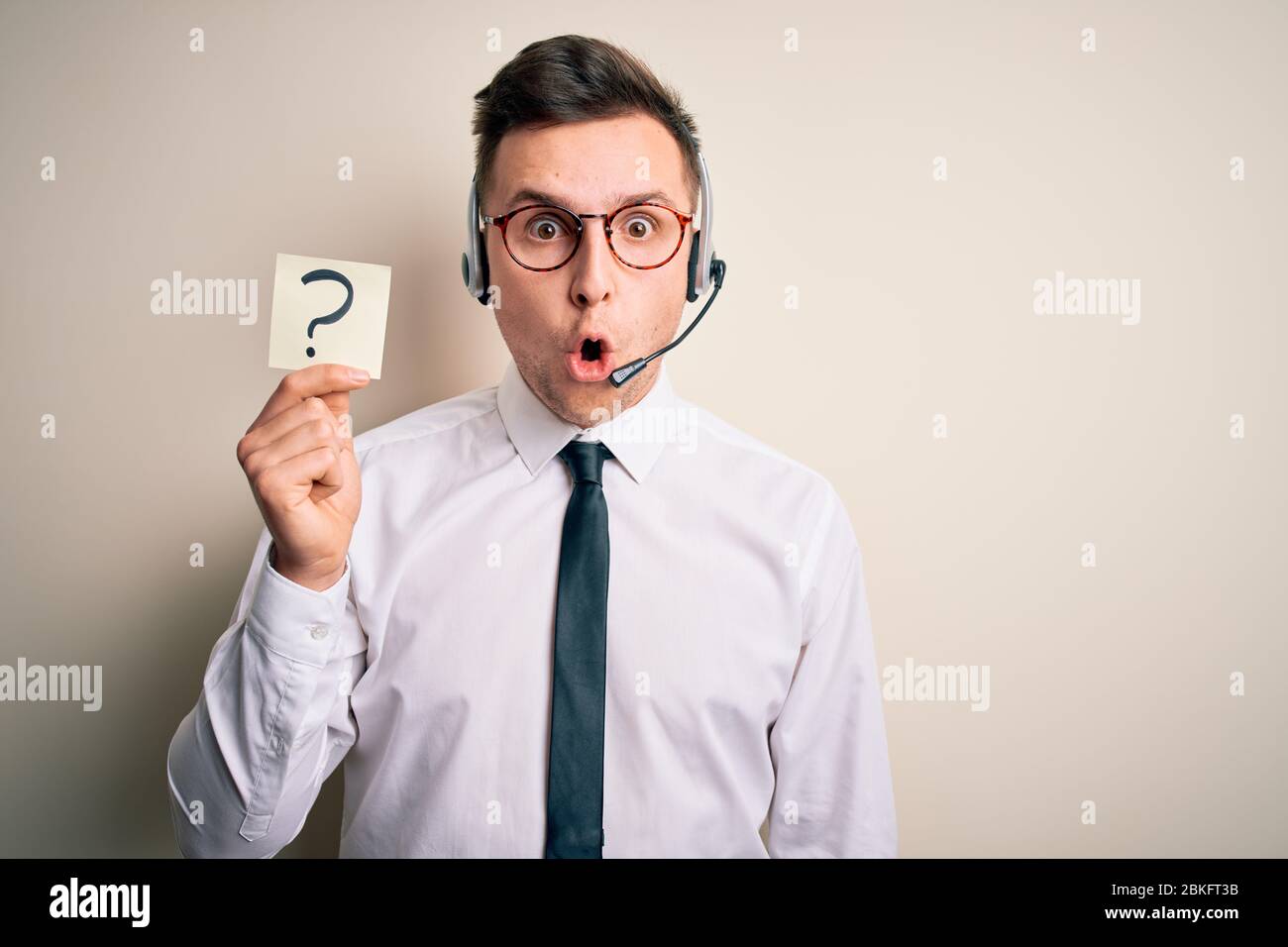 Young call center operator man wearing headset holding paper note with ...