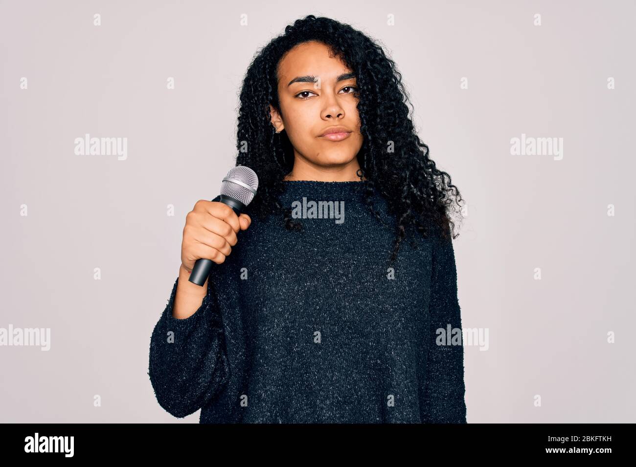 Young african american curly singer woman singing using microphone over ...