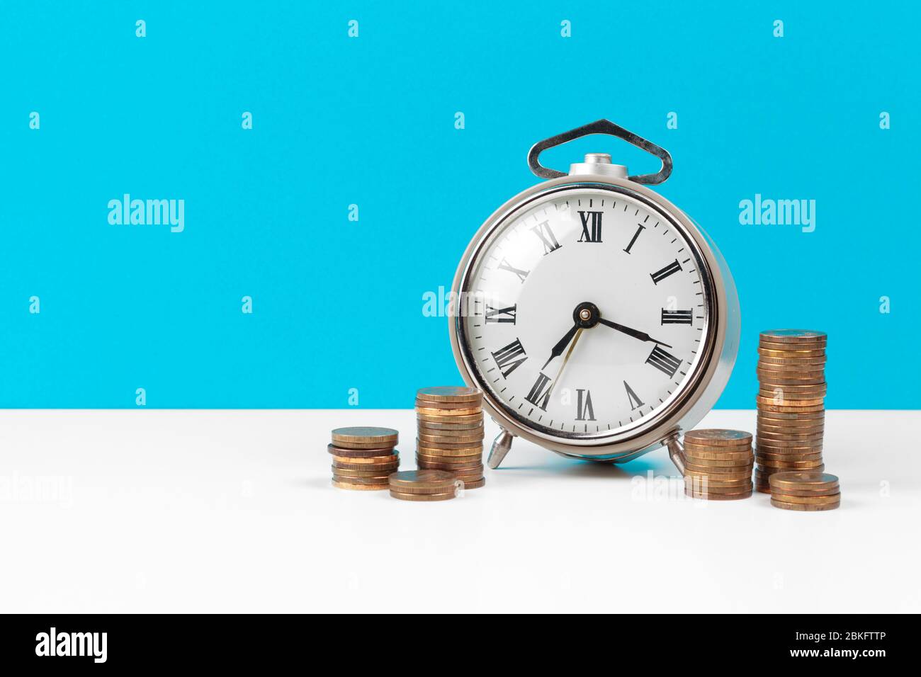 Alarm clock and money coins on the table Stock Photo - Alamy