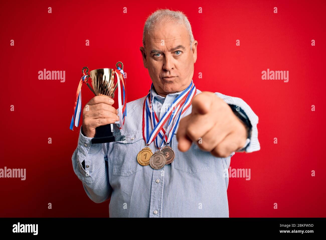 Middle age hoary successful man wearing medals holding trophy over ...