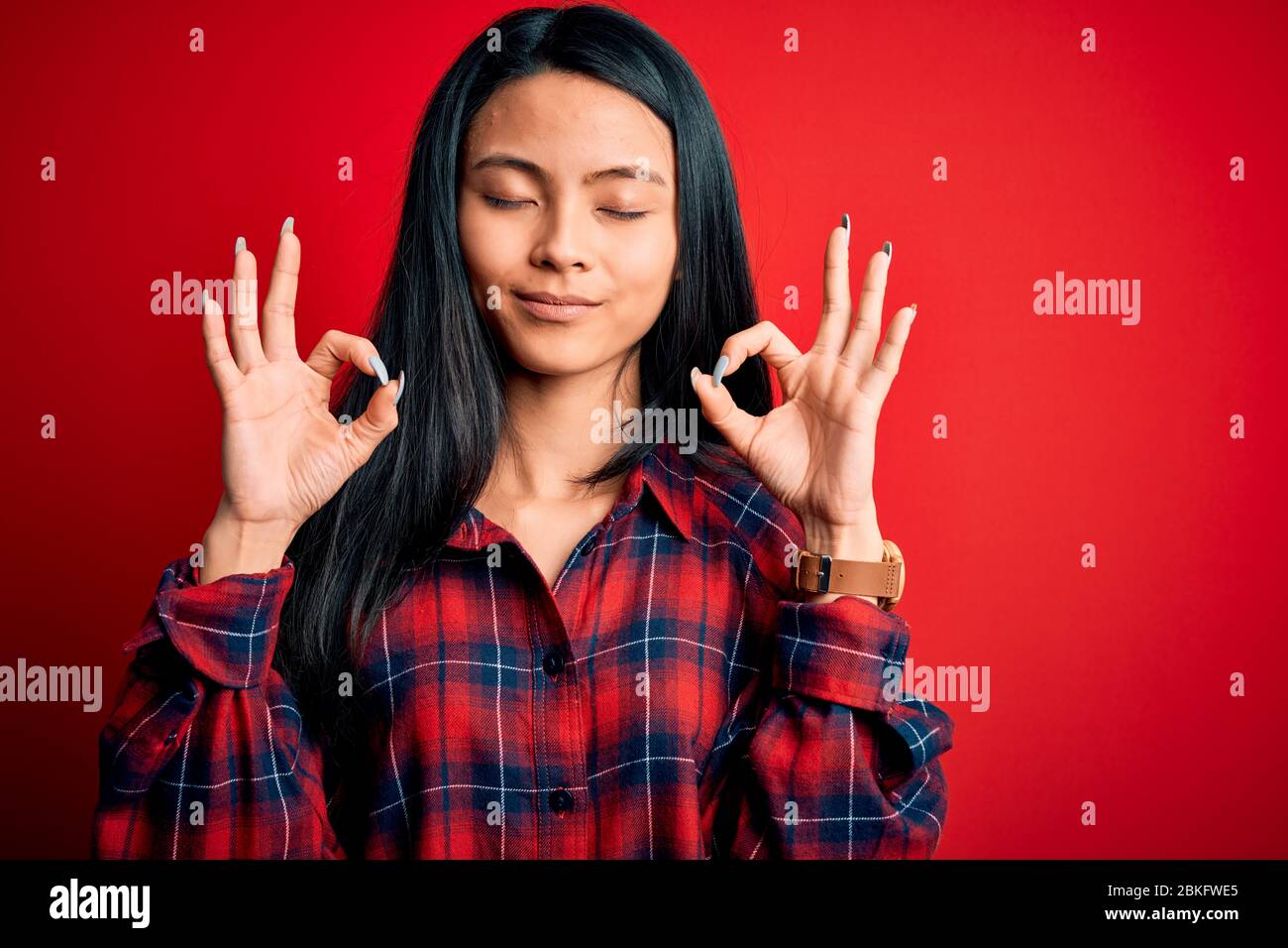 Young beautiful chinese woman wearing casual shirt over isolated red ...