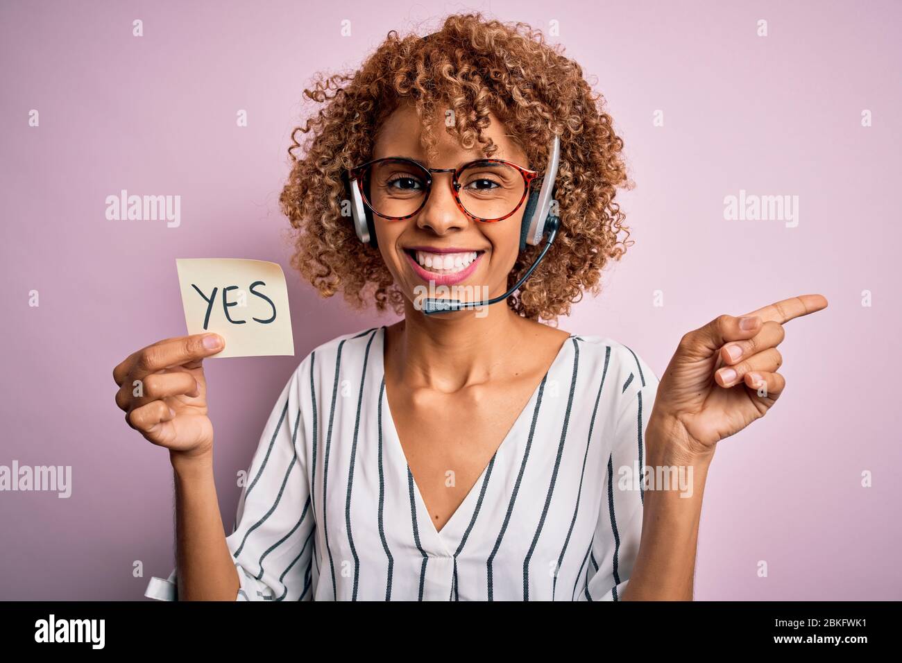 African american call center agent woman using headset holding reminder ...