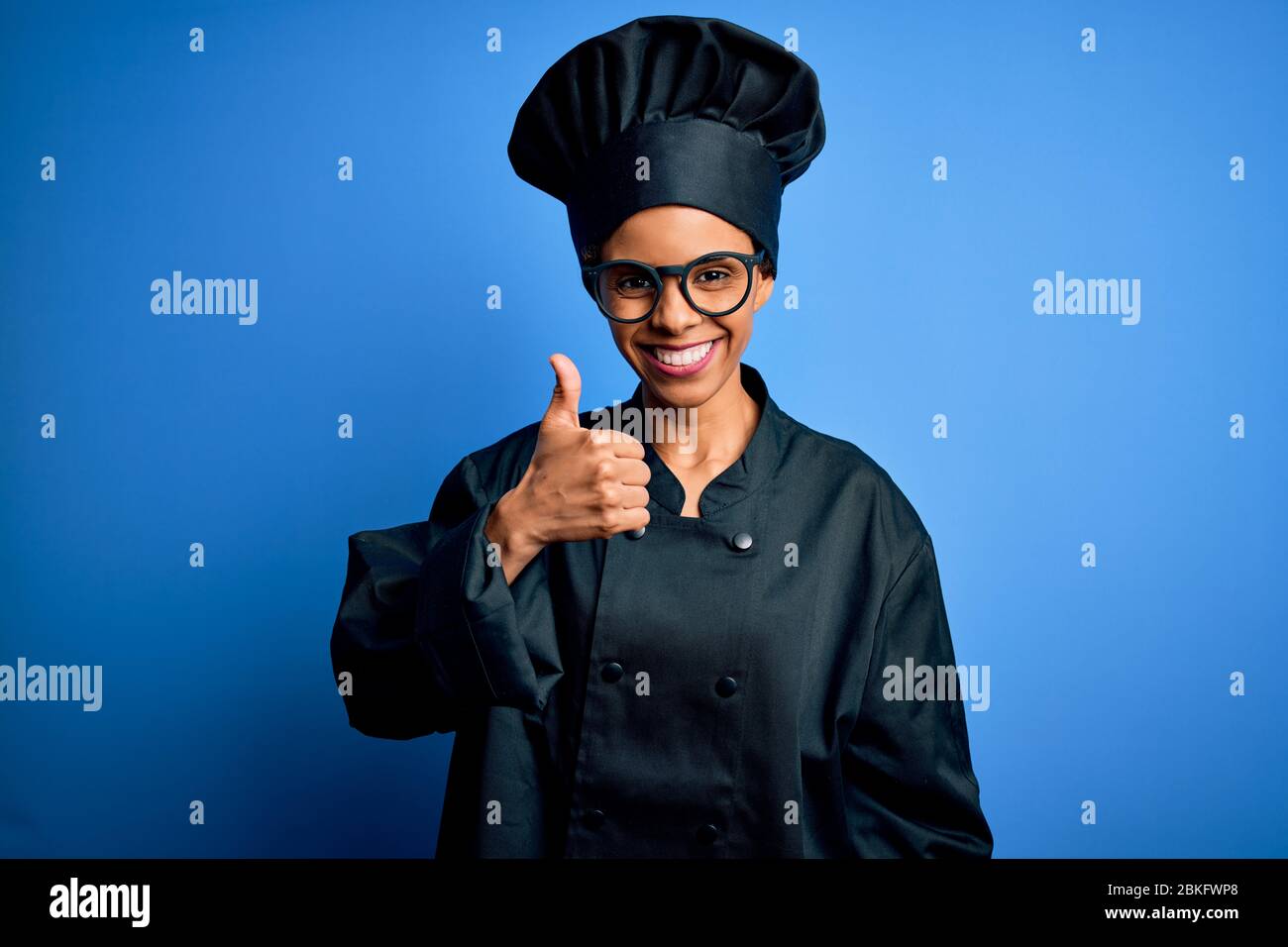 Young african american chef woman wearing cooker uniform and hat over ...