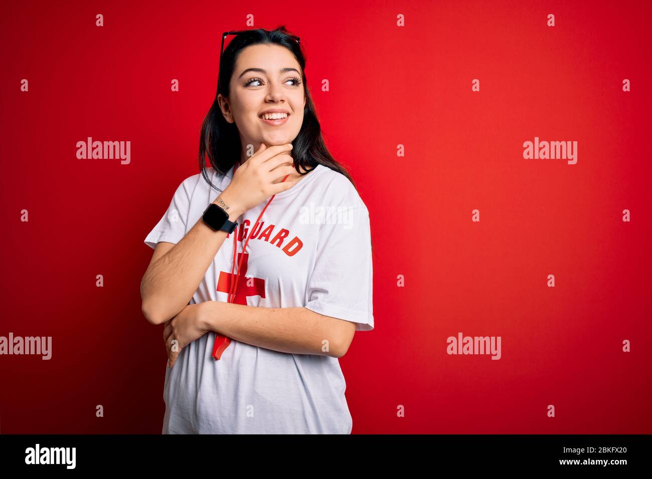 Young lifeguard woman wearing secury guard equipent over red background ...
