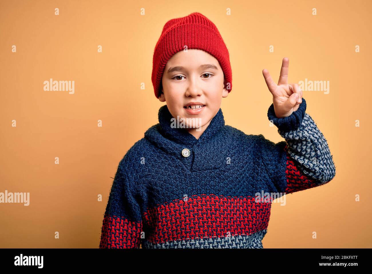 Young little boy kid wearing wool cap and winter sweater over yellow ...