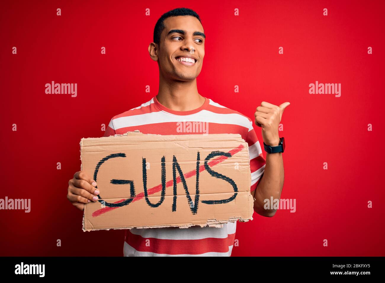 Young handsome african american man holding banner with prohibited guns ...