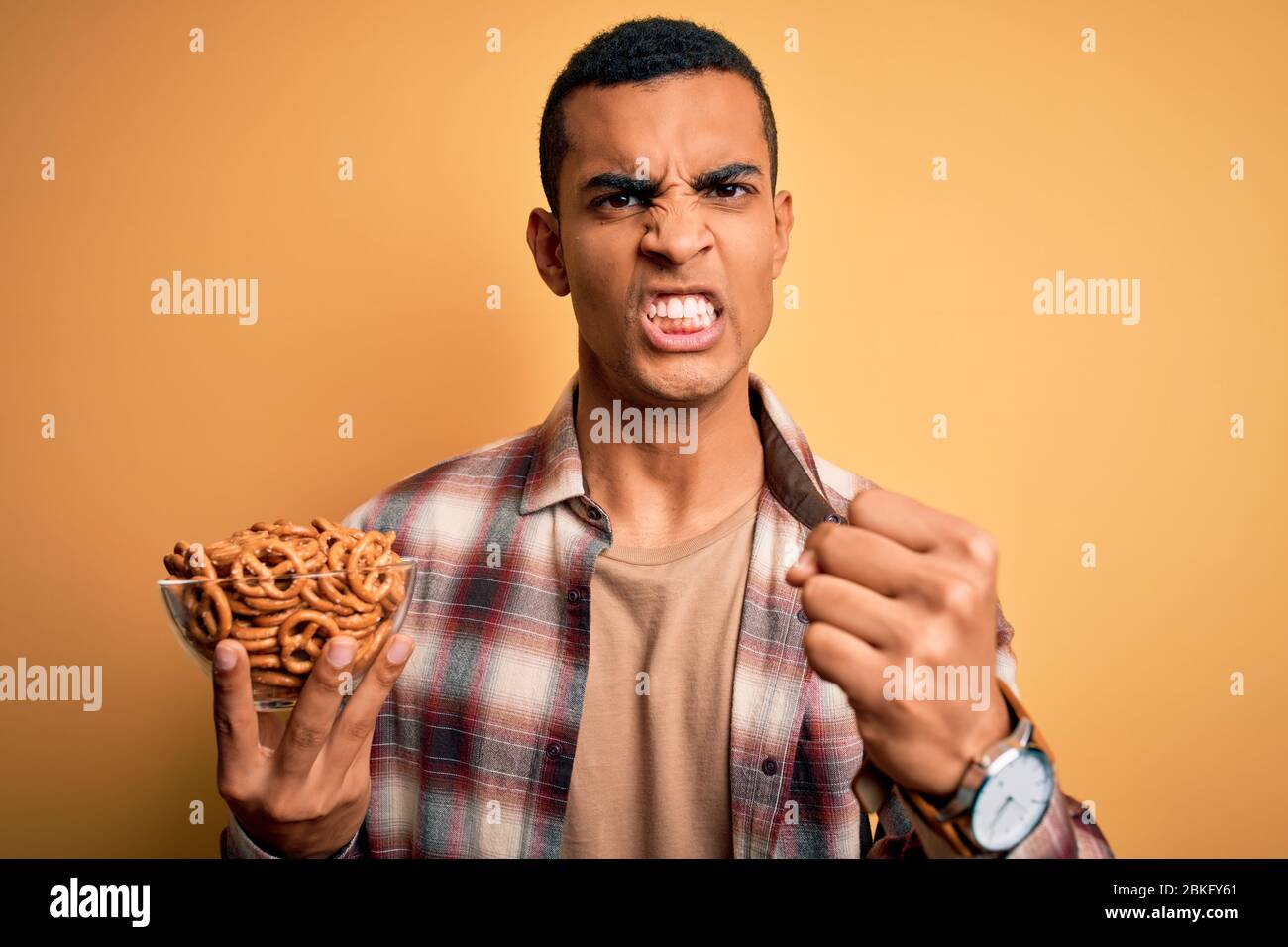 Young handsome african american man holding bowl with german baked ...
