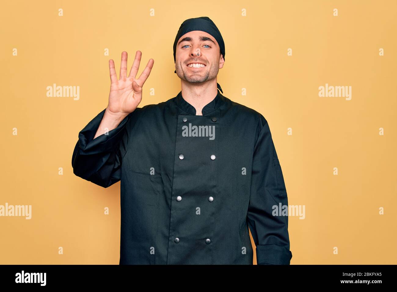 Young handsome cooker man with blue eyes wearing uniform and hat over ...