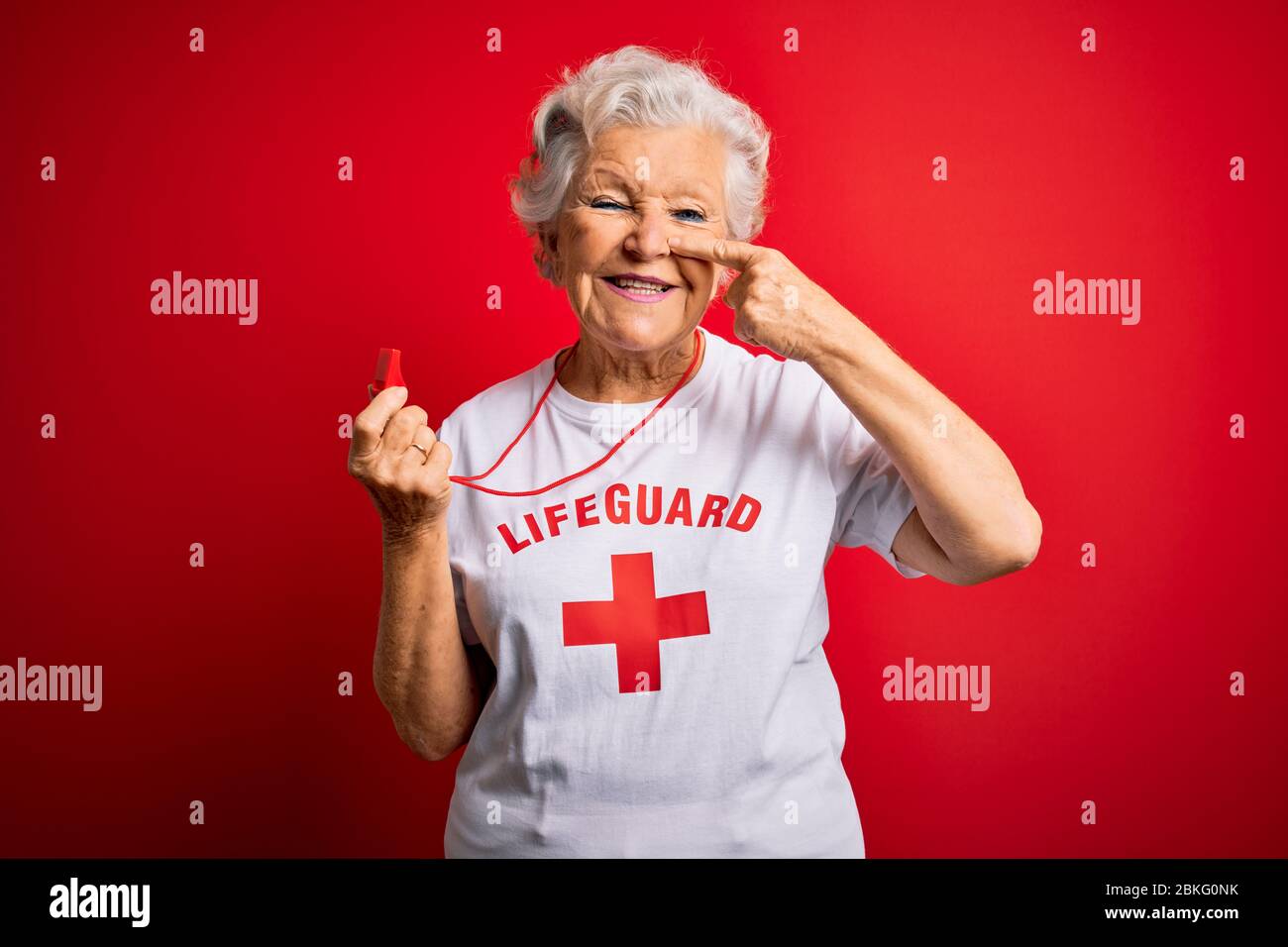 Senior beautiful grey-haired lifeguard woman wearing t-shirt with red ...