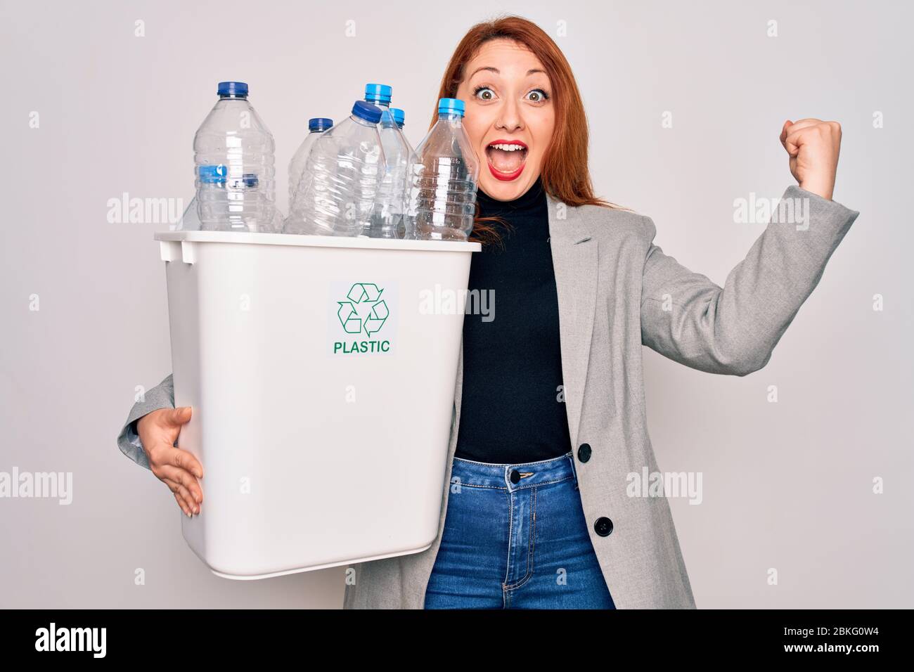 Young beautiful redhead woman recycling holding trash can with plastic ...