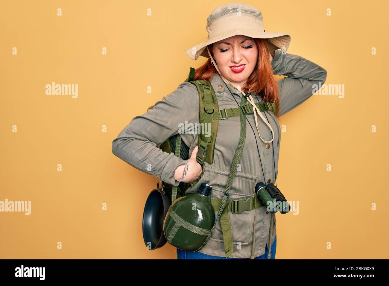 Young redhead backpacker woman hiking wearing backpack and hat over ...