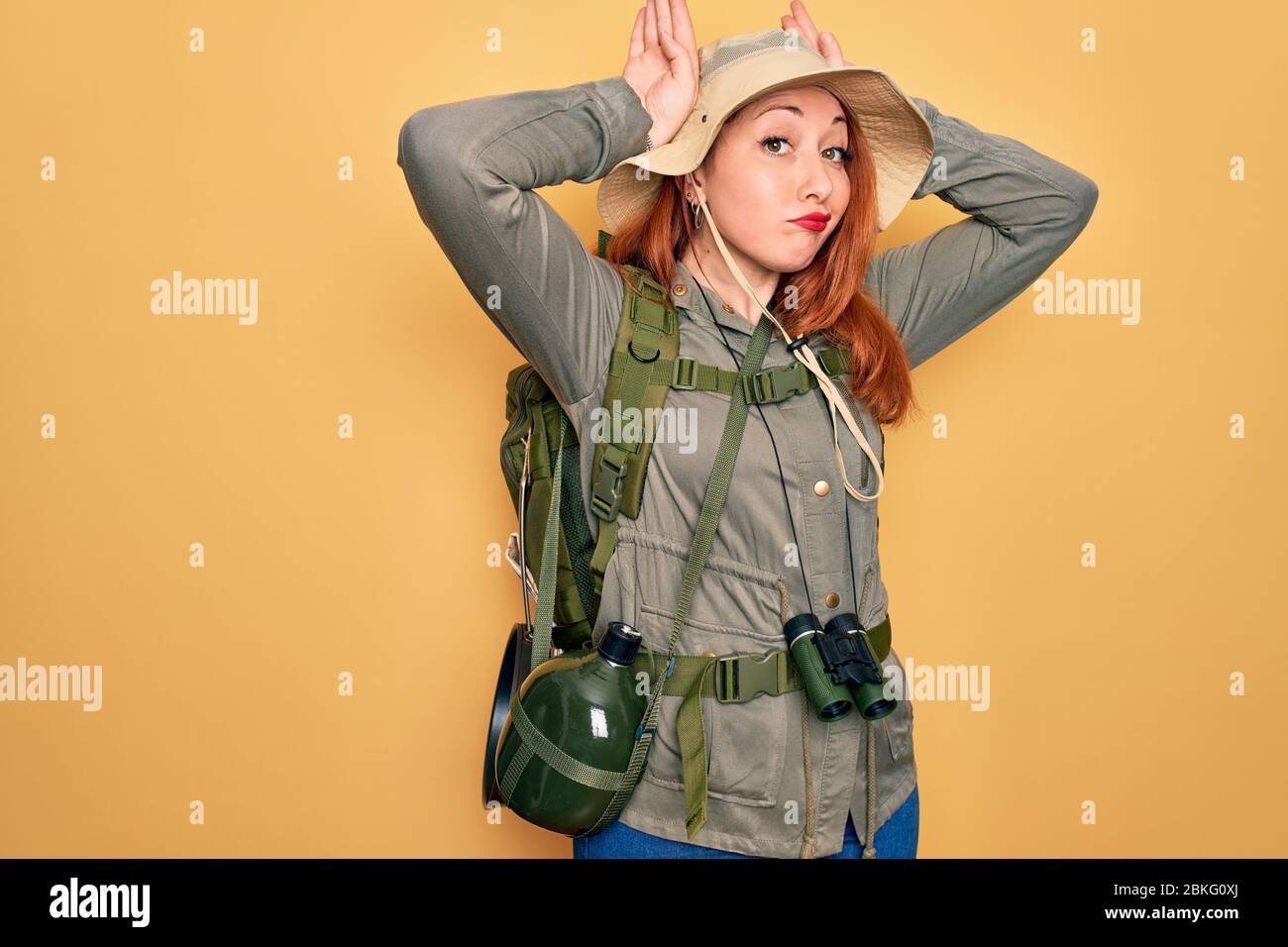 Young redhead backpacker woman hiking wearing backpack and hat over ...