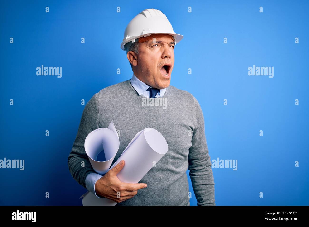 Middle age handsome grey-haired architect man wearing safety helmet ...