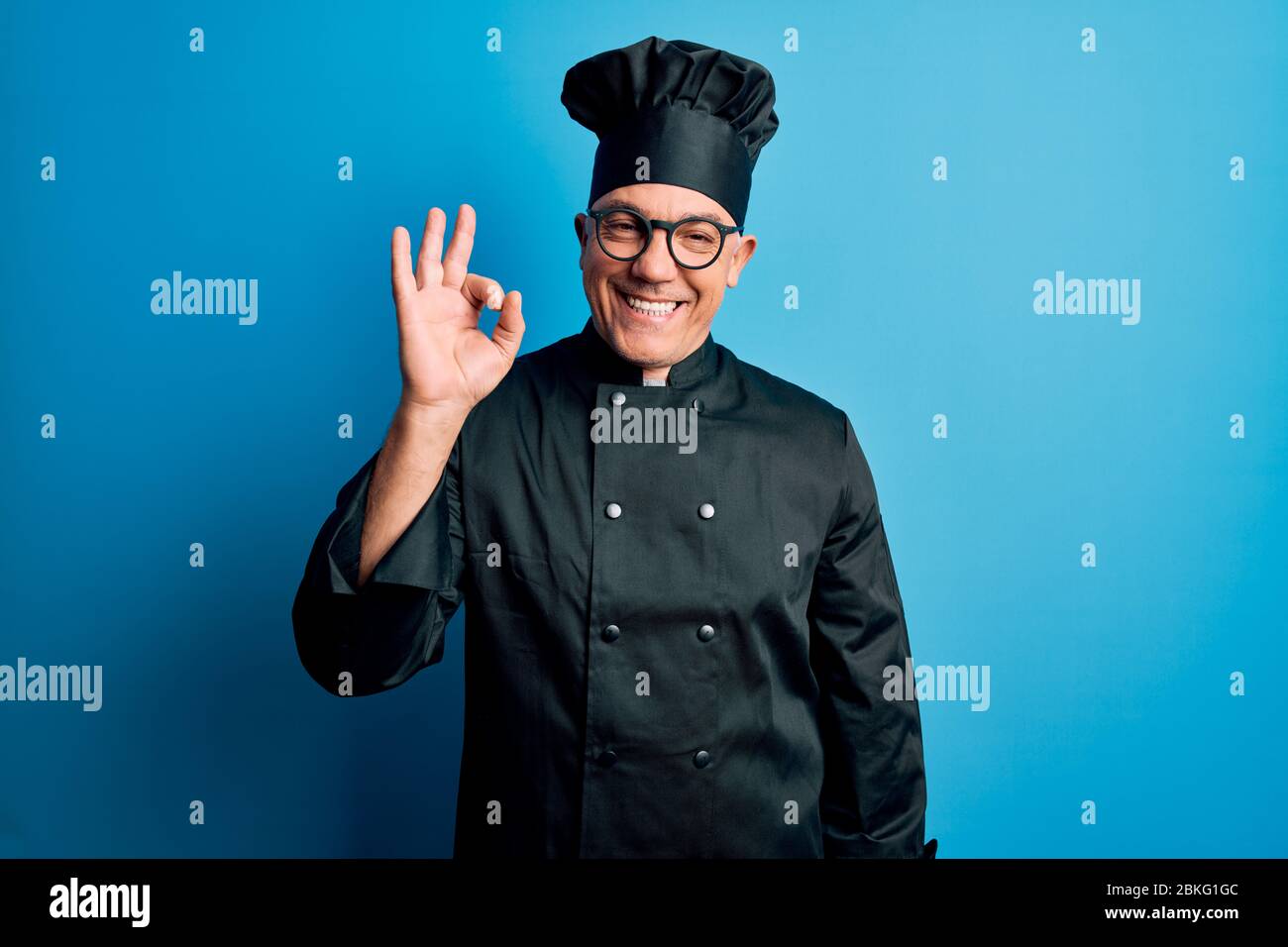 Middle age handsome grey-haired chef man wearing cooker uniform and hat ...