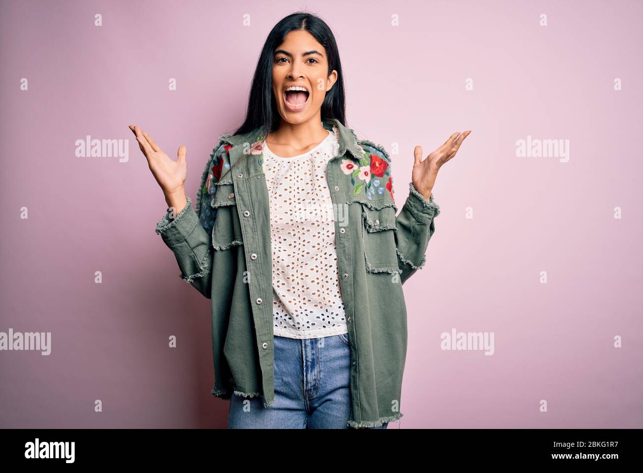 Young beautiful hispanic fashion woman wearing cool jacket over pink ...