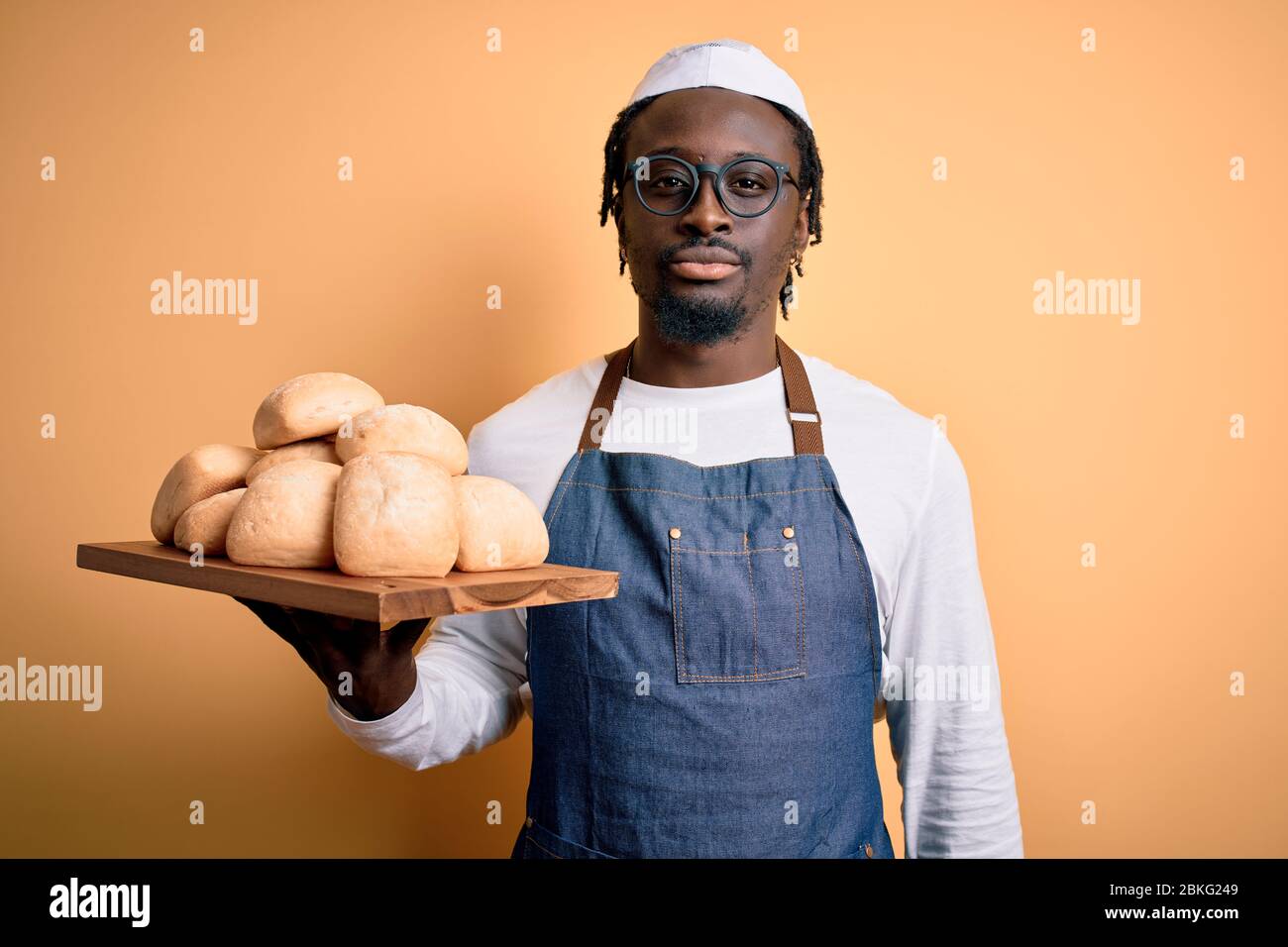 Young african american baker man wearing apron holding tray with ...
