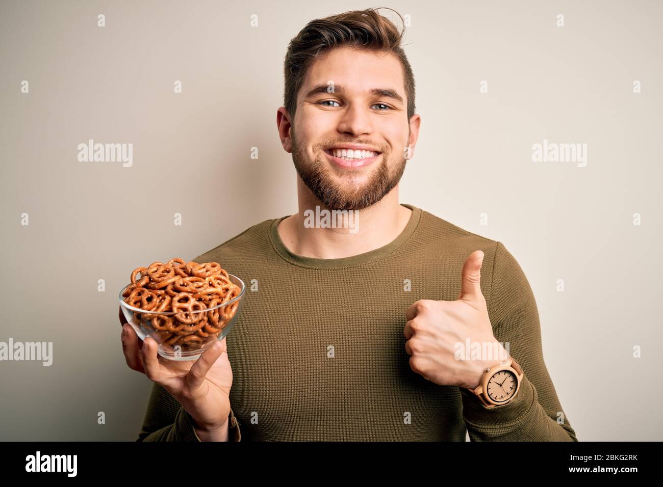 Young blond German man with beard and blue eyes holding bowl with baked ...