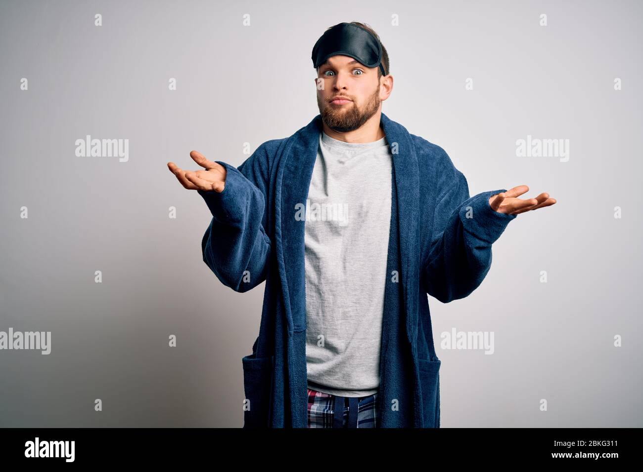 Young blond man with beard and blue eyes wearing sleep mask and pajama ...