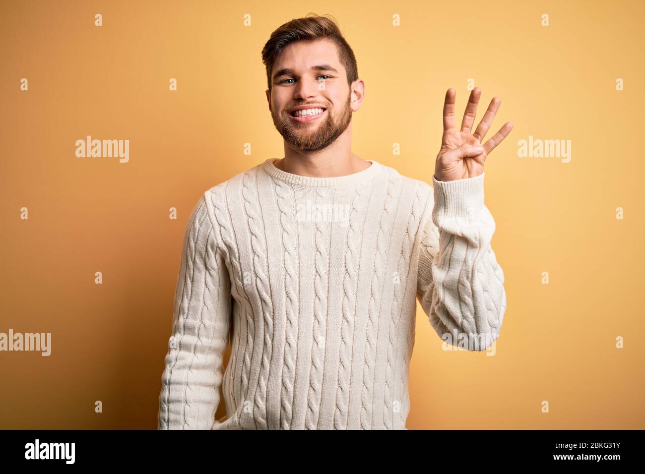 Young blond man with beard and blue eyes wearing white sweater over ...