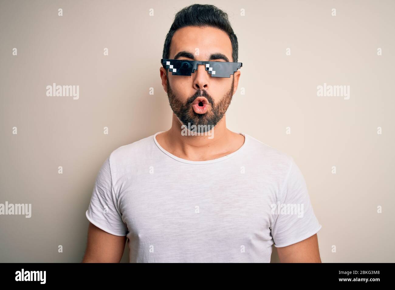 Young handsome man with beard wearing funny thug life sunglasses over ...