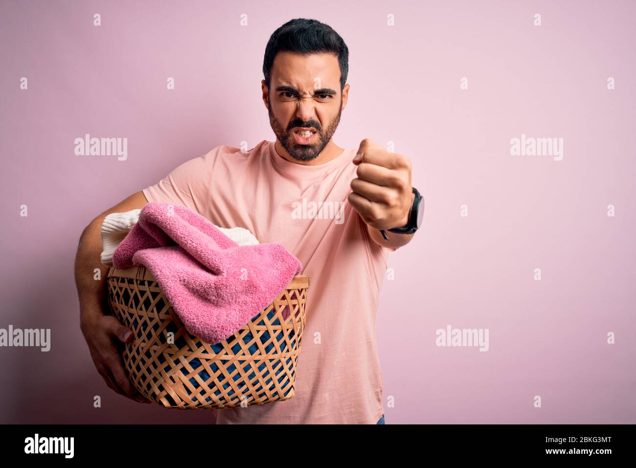 Young handsome man with beard doing housework holding wicker basket ...