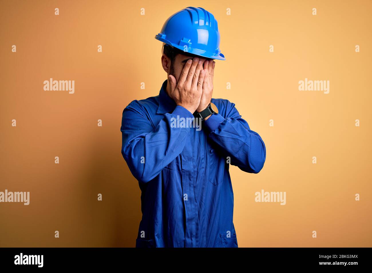 Mechanic man with beard wearing blue uniform and safety helmet over ...