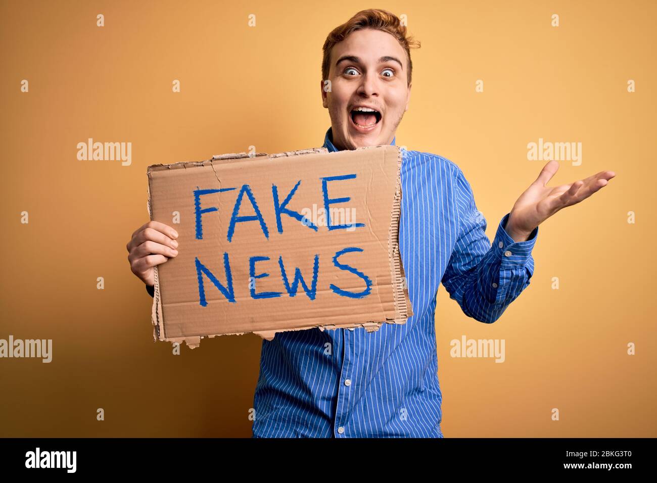 Young handsome redhead man holding banner with fake news message over ...
