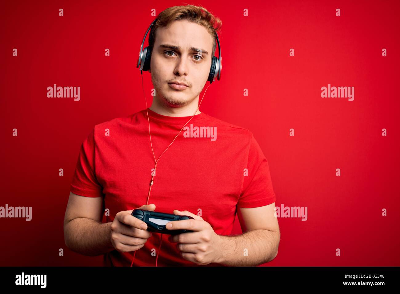 Young handsome redhead gamer man playing video game using headphones ...