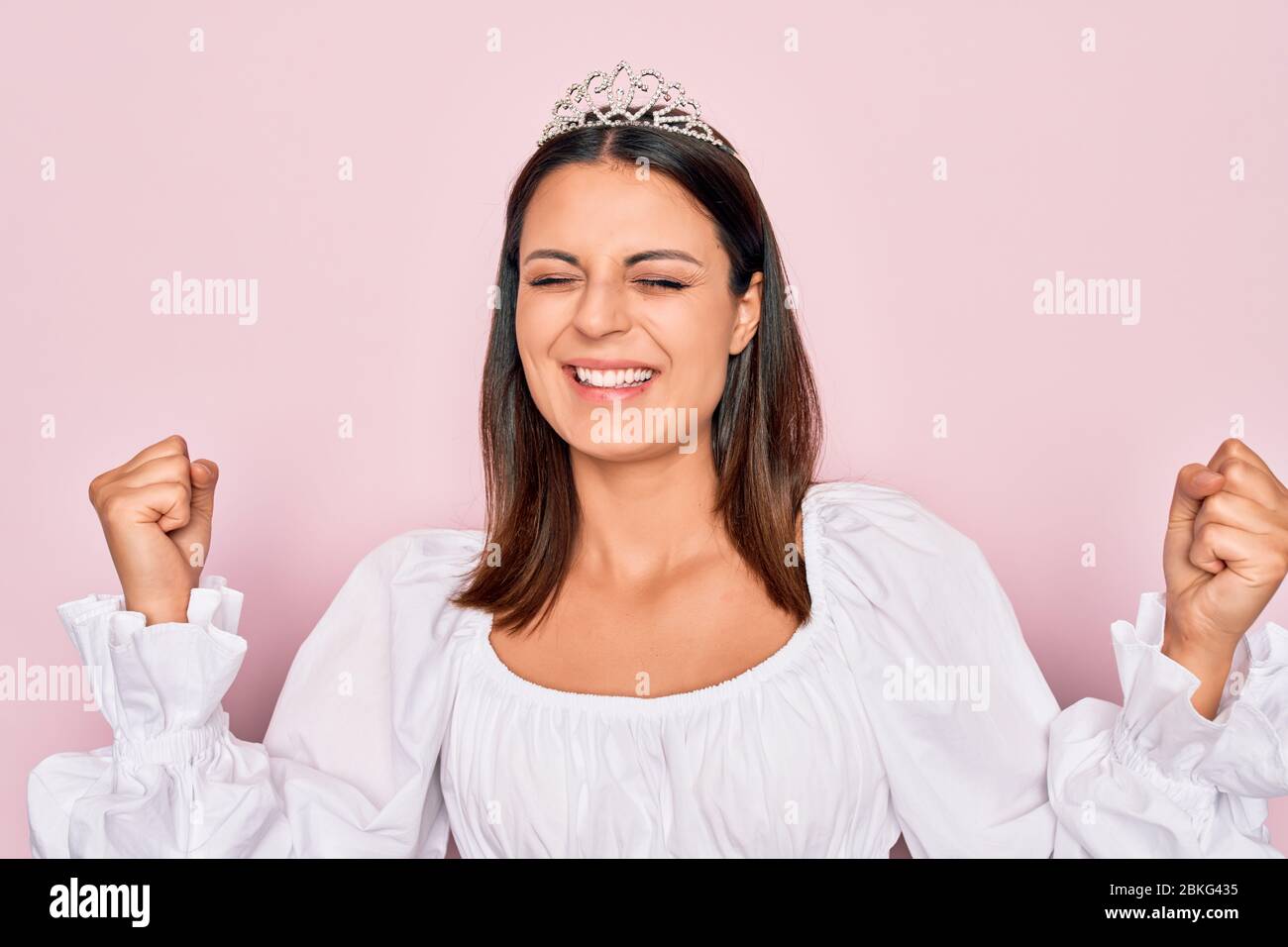 Young beautiful brunette woman wearing princess tiara standing over ...