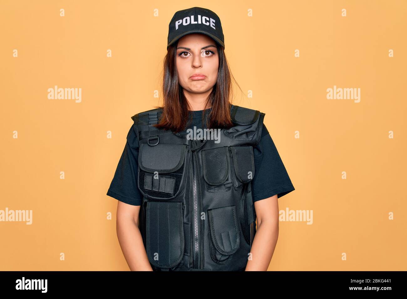 Young beautiful brunette policewoman wearing police uniform bulletproof ...