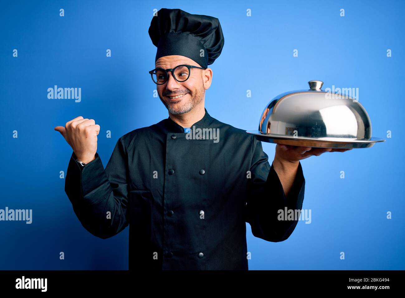 Young handsome chef man wearing uniform and hat holding waiter tray ...